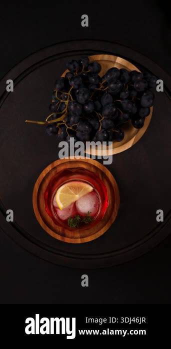 Top down view of a spinning black tray featuring a fresh red cocktail ...