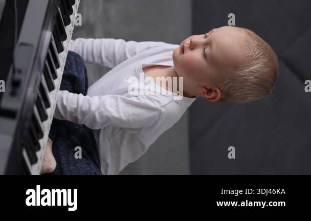 Smiling curious child touching keys of piano. Vertical, 4k footage ...