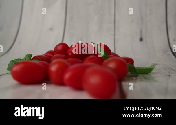 Cherry tomatoes spilling from glass jar on white wooden table.Fresh red ...