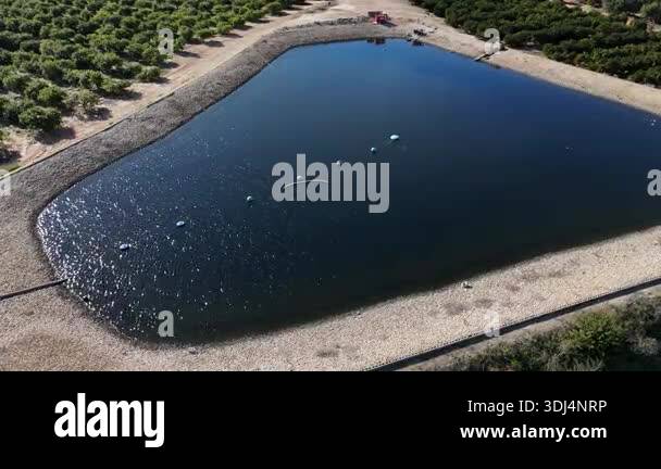 Drone aerial of artificial irrigation reservoir surrounded by farmland ...