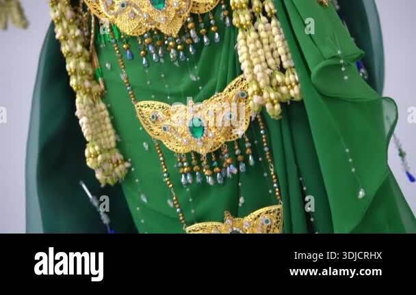 A smooth panning shot revealing the details of a green Javanese dress ...