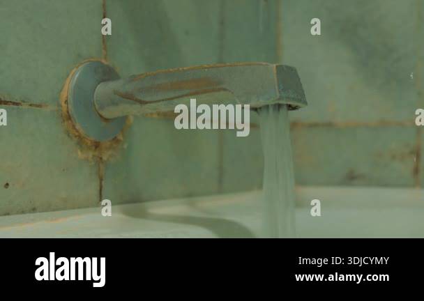 Detailed shot of an aged and slightly rusted metallic faucet pouring ...