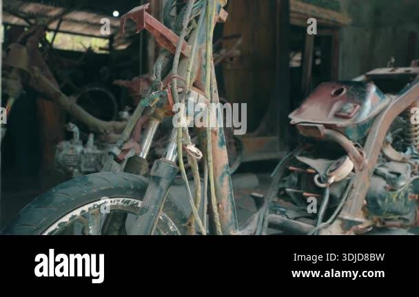 A close-up of a motorcycle frame and parts, heavily rusted and deformed ...