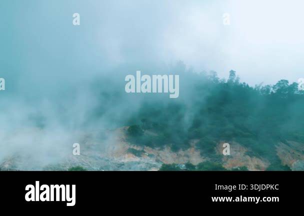 A dramatic view of thick white mist and geothermal steam rising from ...