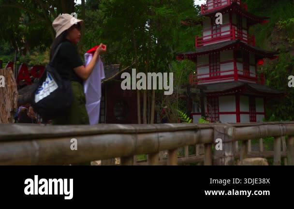 A young woman holding the Indonesian flag walks along a wooden railing ...