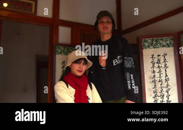 A young, happy Asian couple poses for a photo in a traditional Korean ...