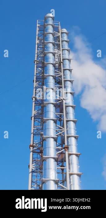 Tall chimney of a mini-boiler room releasing white smoke against a blue ...