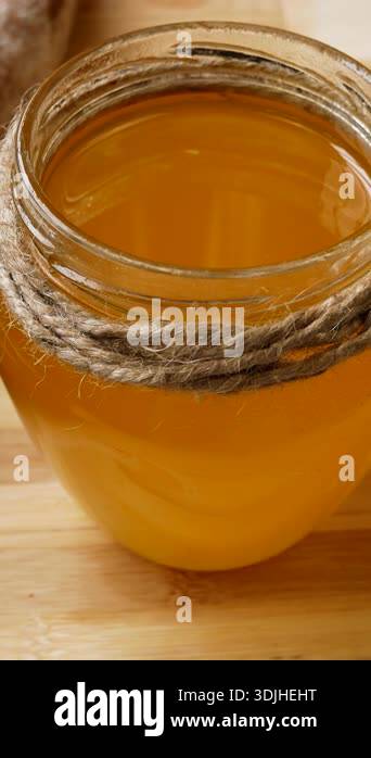 A jar of golden sweet honey on the table, next to a baguette and a ...