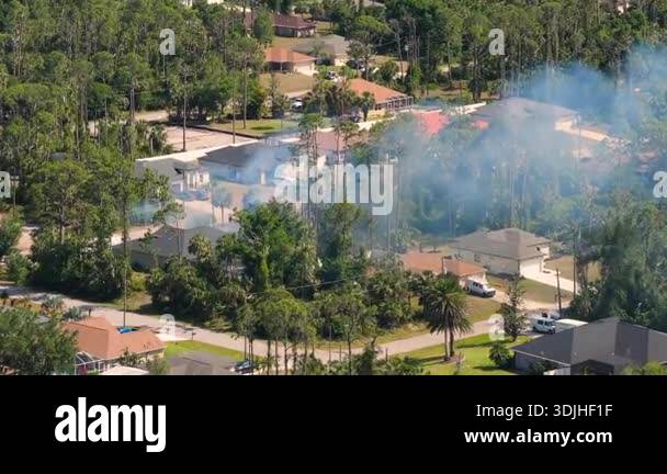 Vegetation fire burns through forested area near suburban houses in ...