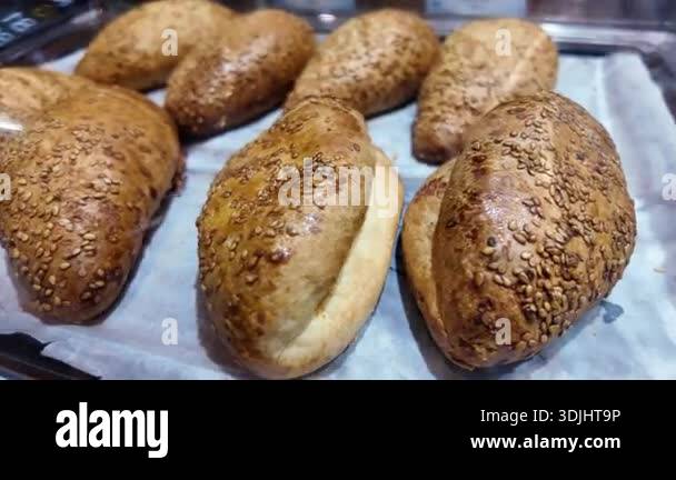 Bakers prepare fresh bread rolls with sesame seeds for customers Stock ...
