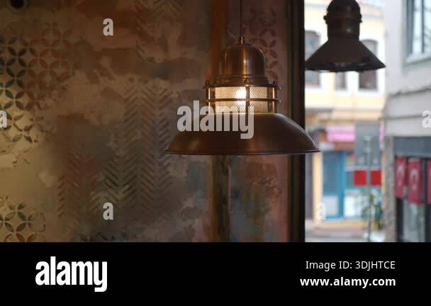 A light fixture shines inside a cafe while the city is visible outside ...