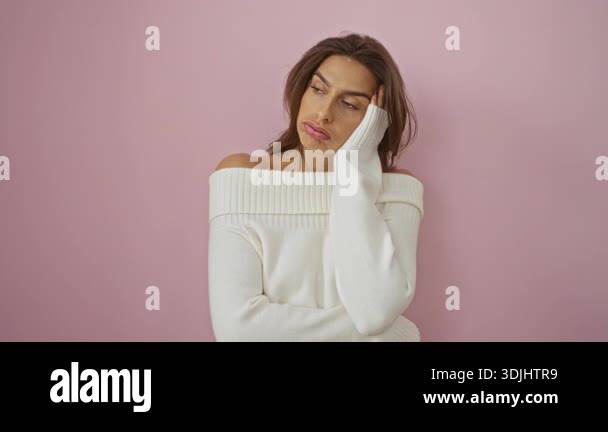 Woman wearing white sweater poses thoughtfully against pink wall ...