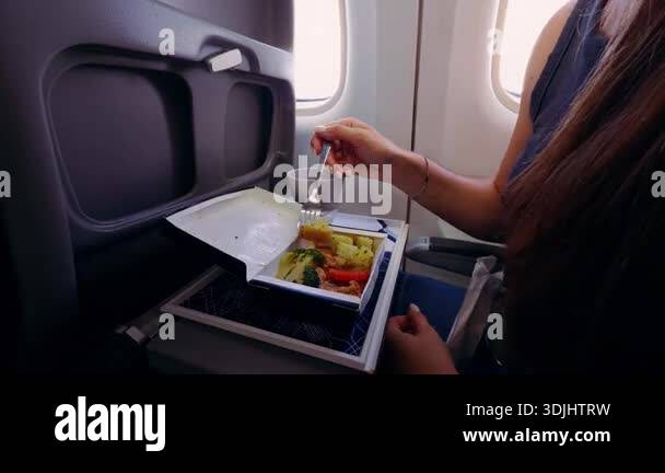 Woman Eating Airline Meal at Tray Table inside Aircraft Cabin captured ...