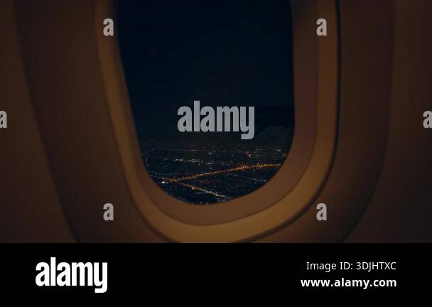 Low Angle Aircraft Window Scene showing City Lights Grid at Night ...