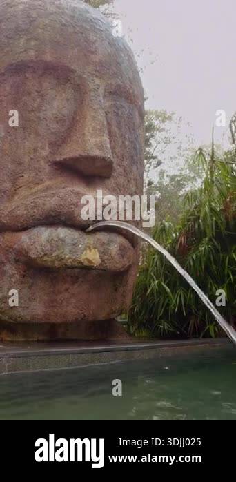 Vertical video. Massive Stone Face Fountain Pouring Water Into Pool ...