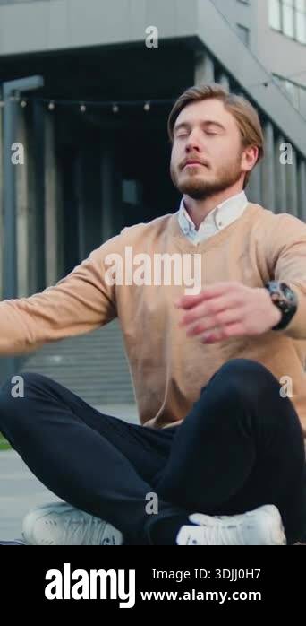 Handsome office man relaxing in the lotus position, sitting in front of ...