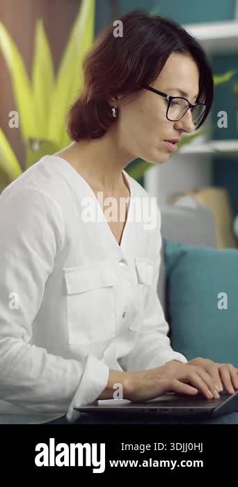 Woman uses laptop at home while sitting on a couch, success winning ...