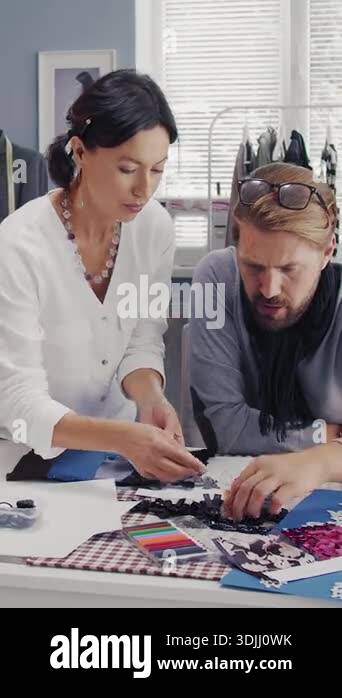 Man and woman work on fabric samples in a bright studio with colorful ...