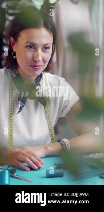 Woman works at the sewing table with beads and fabric in a vibrant ...