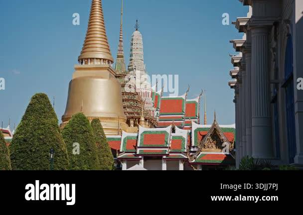 Handheld shot of ornate golden chedis and traditional roofs of the ...