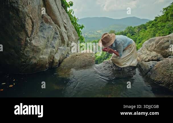 Middle-aged woman washing hands in clean natural rock pool at tropical ...