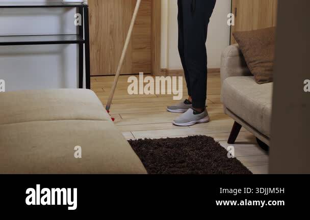 Young woman sweeping the floor of her apartment as part of her daily ...