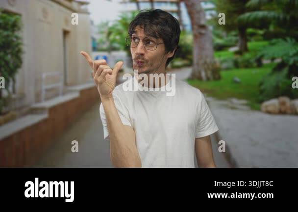 Man pinches nose with hand in green park street scene wearing ...