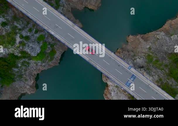 Luxury red cabriolet with model crossing bridge by river from above ...