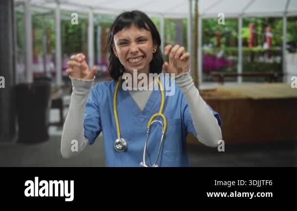 Woman nurse with yellow stethoscope and blue scrubs hands clawing ...