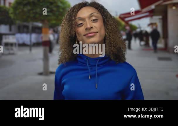 Woman in blue hoodie with curly hair pointing fingers with both hands ...