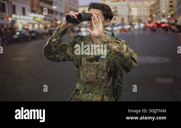 Soldier man in camouflage uniform holds binoculars to eye and gestures ...