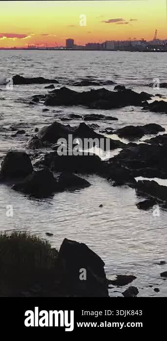 Vertical fixed camera video of a sunset over the rocky coast of ...