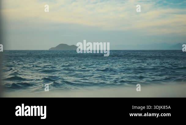 Wide ocean view with gentle waves and a distant island on the horizon ...