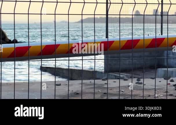 Barrier at the waterfront near the water during evening hours. A fence ...
