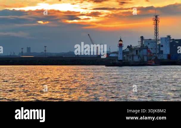 Sunset over harbor with lighthouse and industrial landscape. Sunset ...