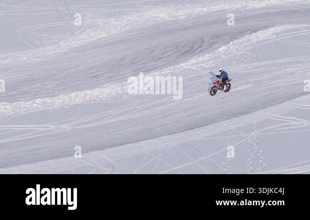 Aerial view shows a rider on a red dirt bike circling a groomed oval on ...