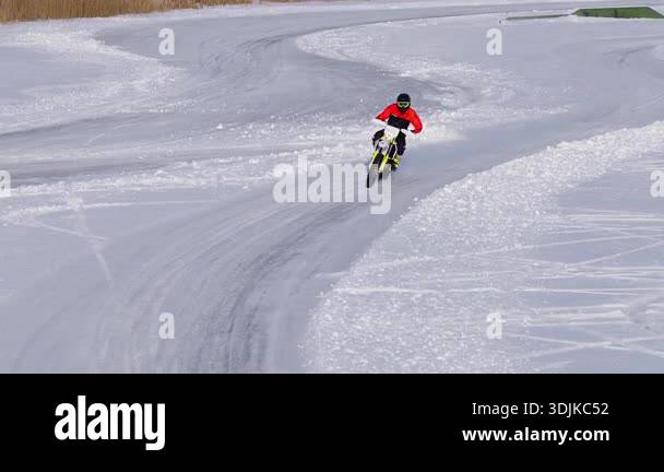 Aerial view of a lone rider in red and neon yellow leans on a studded ...