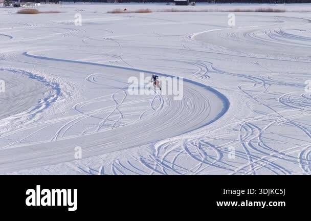 Aerial view shows a motorcyclist drifting and turning on a frozen lake ...