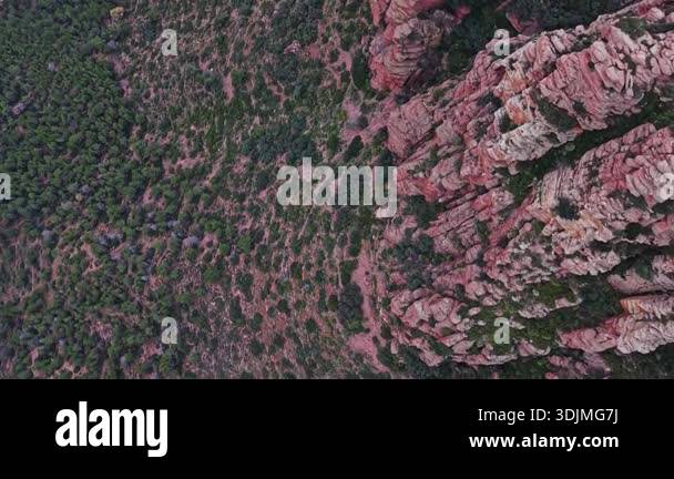 Tall cliffs rise over green trees in a natural area of Spain. The scene ...