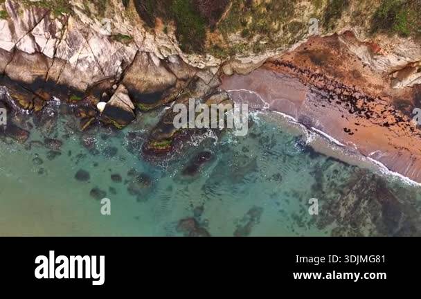 Aerial view captures a stunning coastal scene with rugged cliffs, calm ...