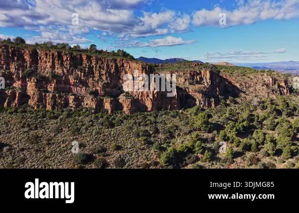 Cliffs rise steeply in Spain, surrounded by green trees and shrubs ...