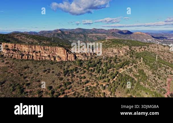 A group of people walks along a trail on a mountain in Spain. The sky ...