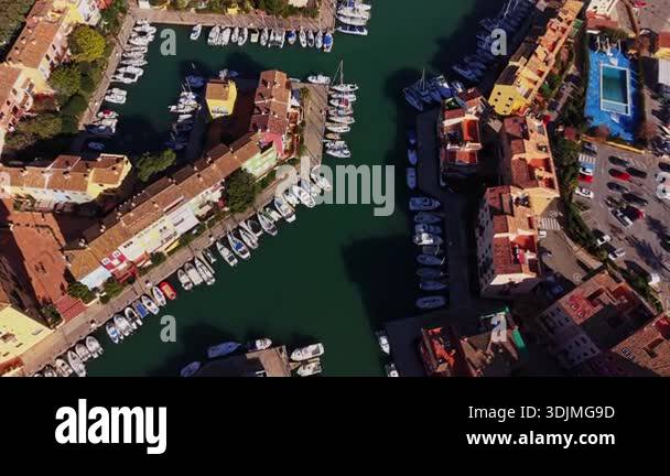 Many boats are docked along the sides of a canal in Spain. Buildings ...