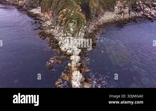 This aerial view captures a rugged coastline highlighted by textured ...