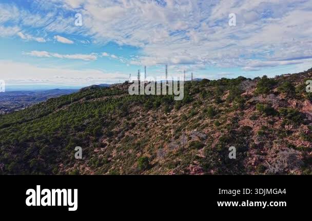 A view of mountains in Spain features green trees and radio towers. The ...