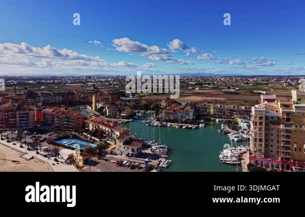 A coastal scene in Spain shows boats in a harbor near colorful ...