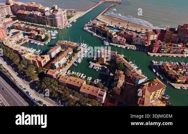 Aerial view shows a marina in Spain with many boats docked. Buildings ...