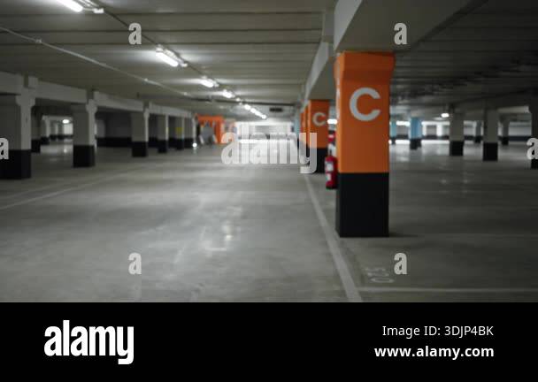 Blurred parking garage interior with concrete floor, orange column ...