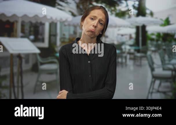 Woman pouting with arms crossed on a restaurant terrace outdoors near ...