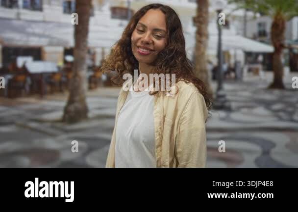 Woman pointing hand toward camera on a sunny street plaza with palm ...